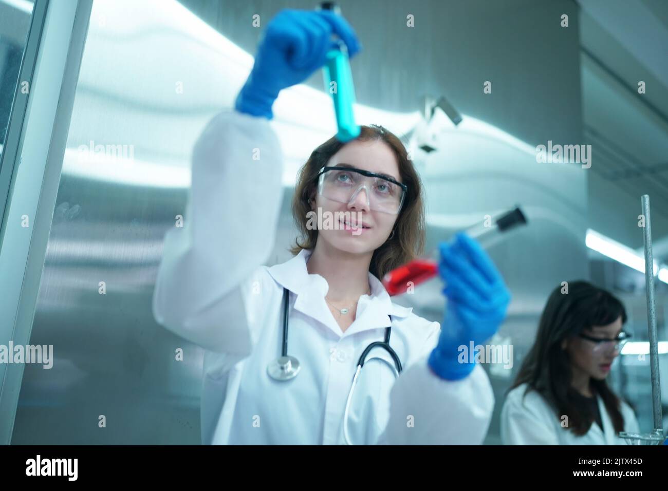 Young scientist in white lab coat working with binocular microscope in ...