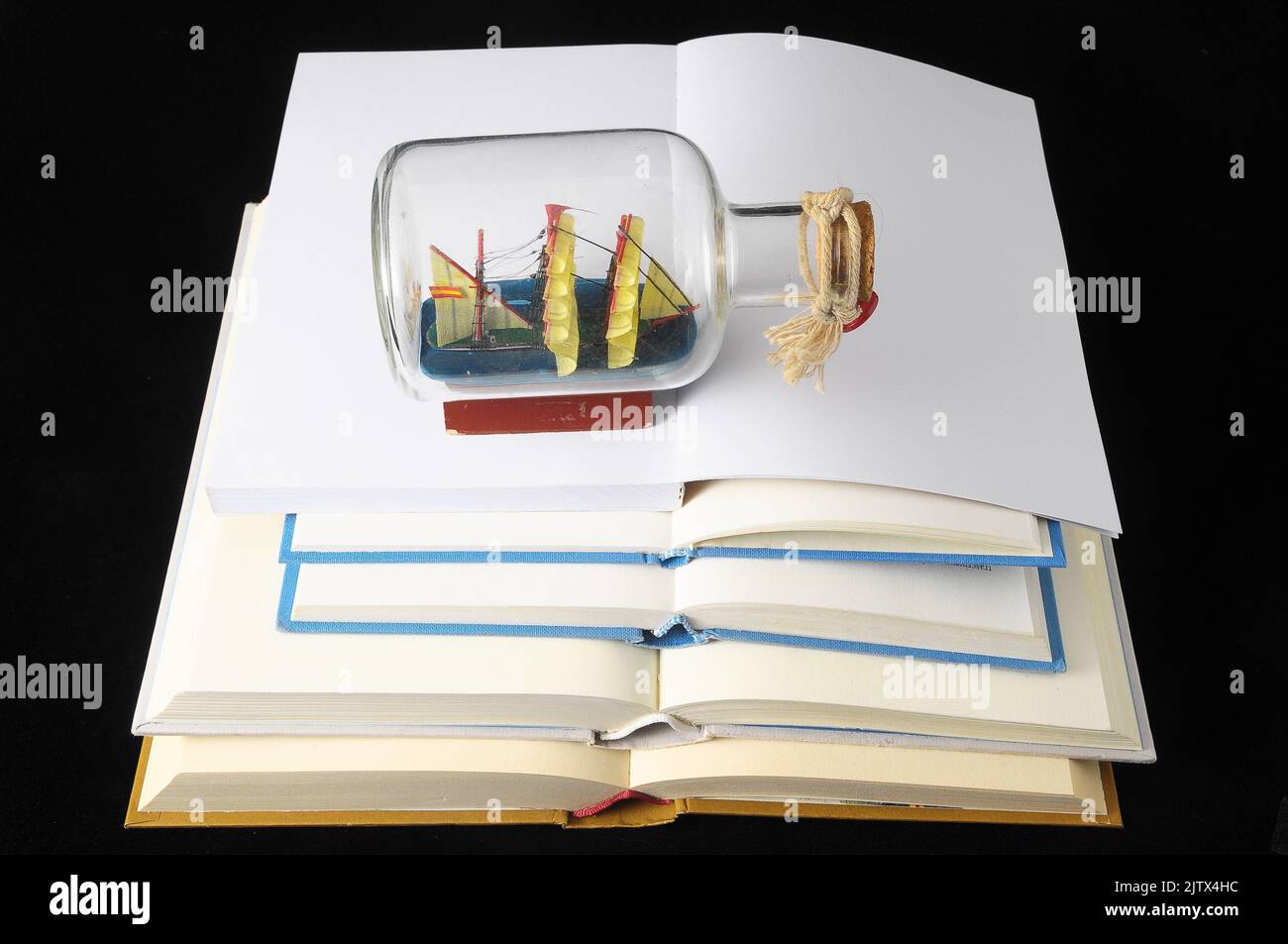 A sailing boat inside a glass bottle over the stack of open empty ...