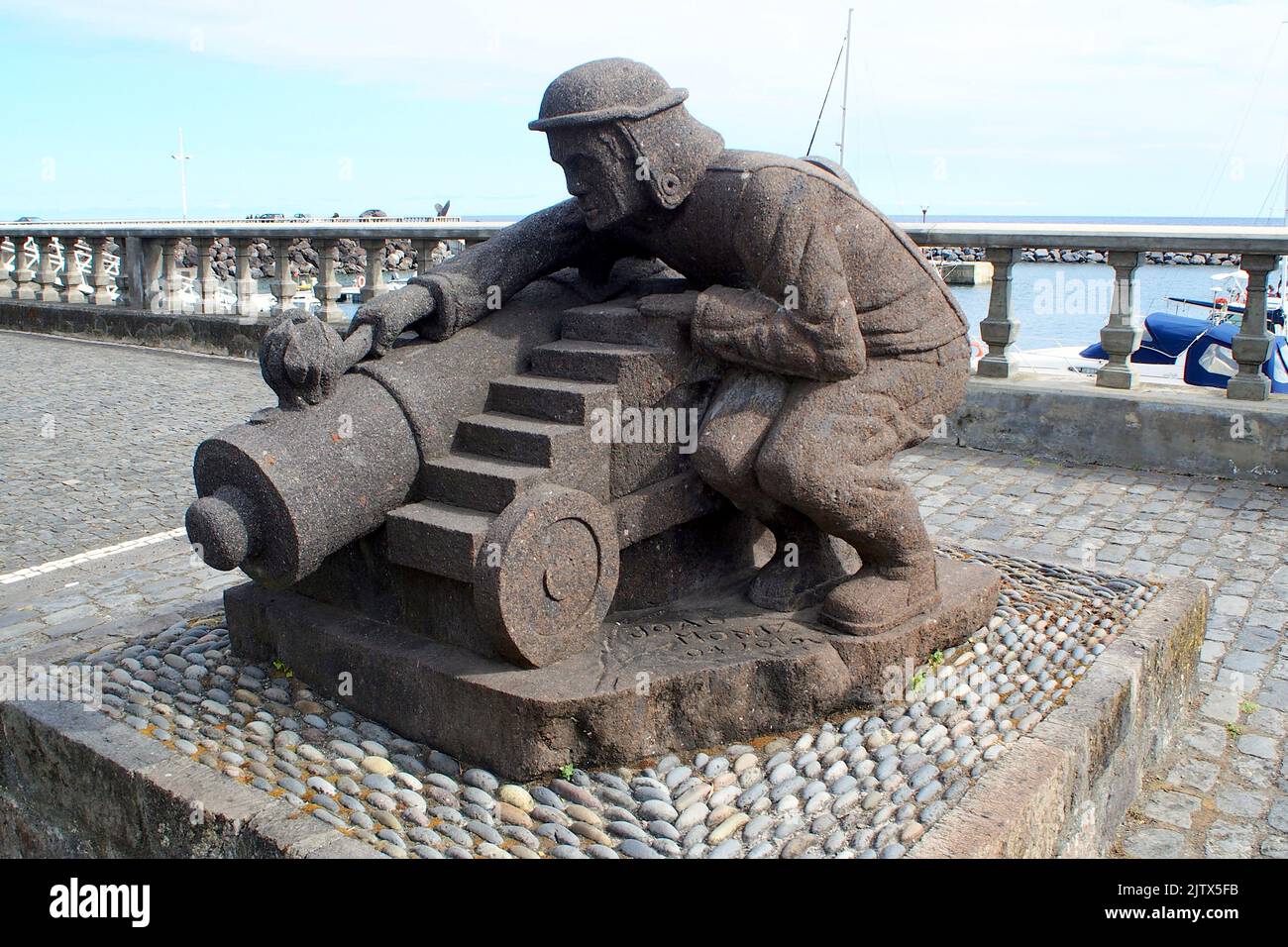 Stone sculpture of a cannoneer lighting a fuse of a naval gun facing ...