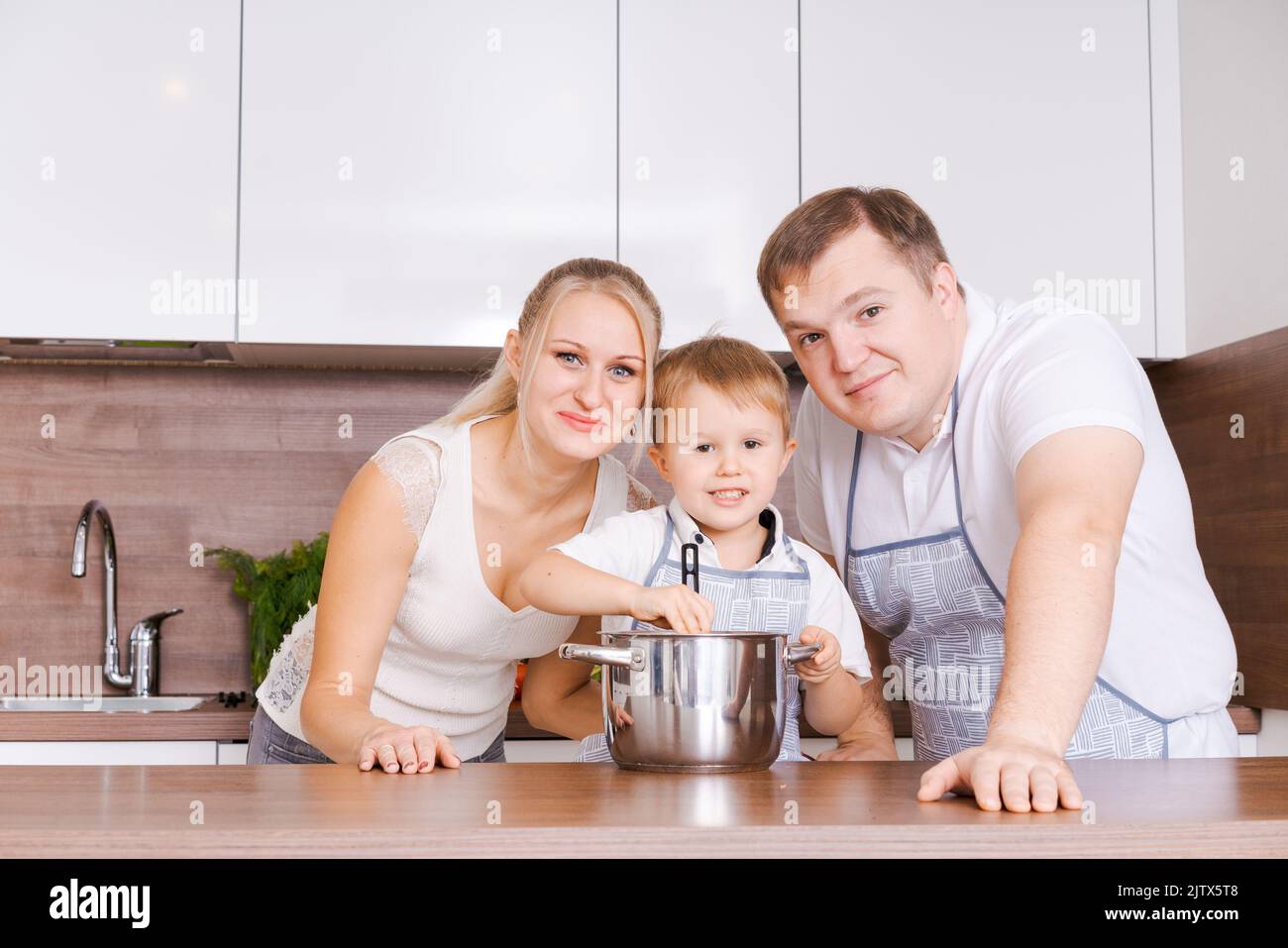 Kind caucasian parents teaching their little adorable son how to cook ...