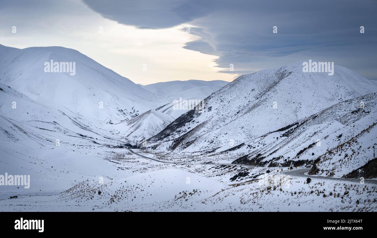 The long and winding road at Lindis Pass covered in snow, South Island ...