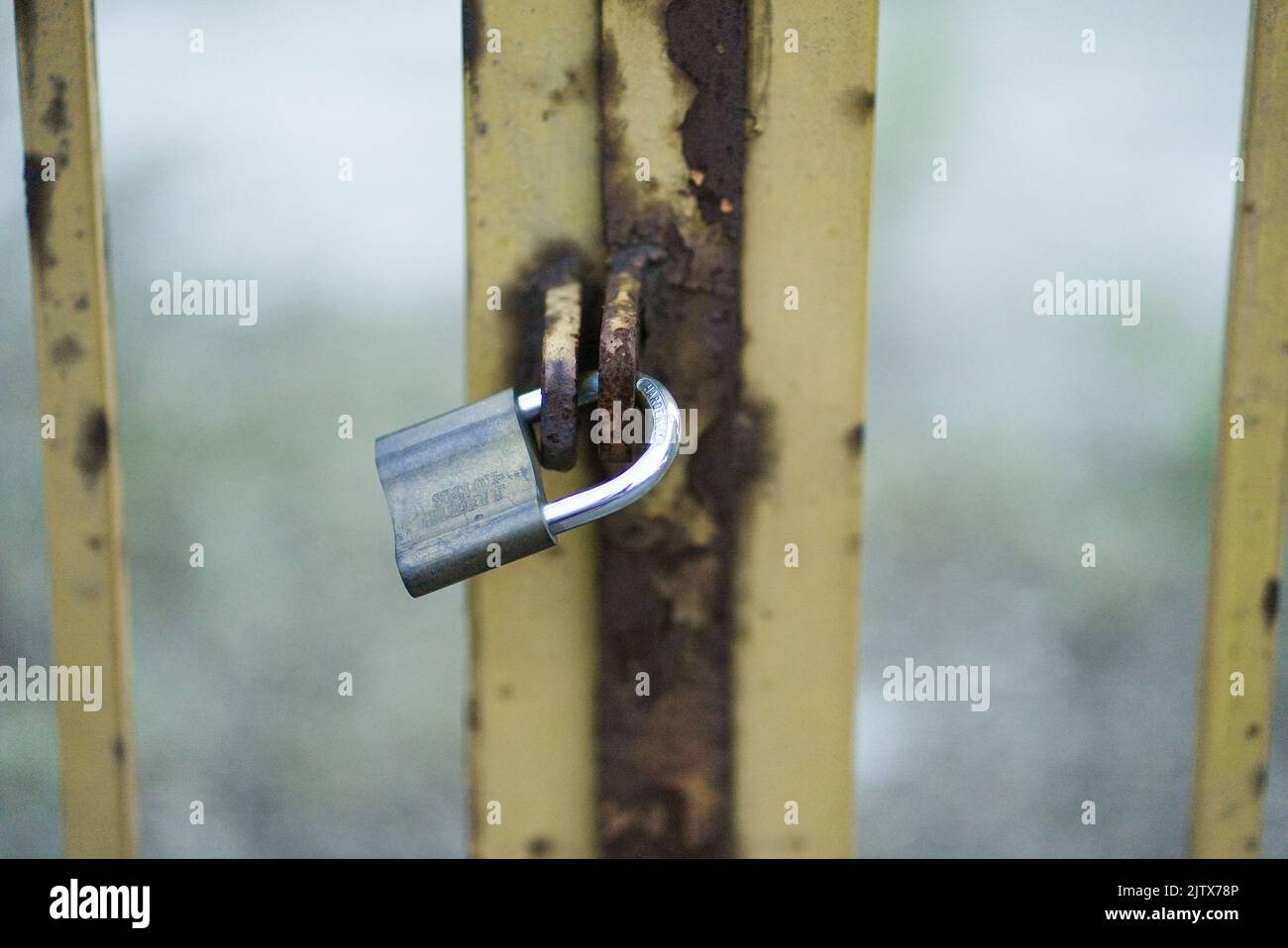 grey lock on a yellow gate pressed together Stock Photo - Alamy