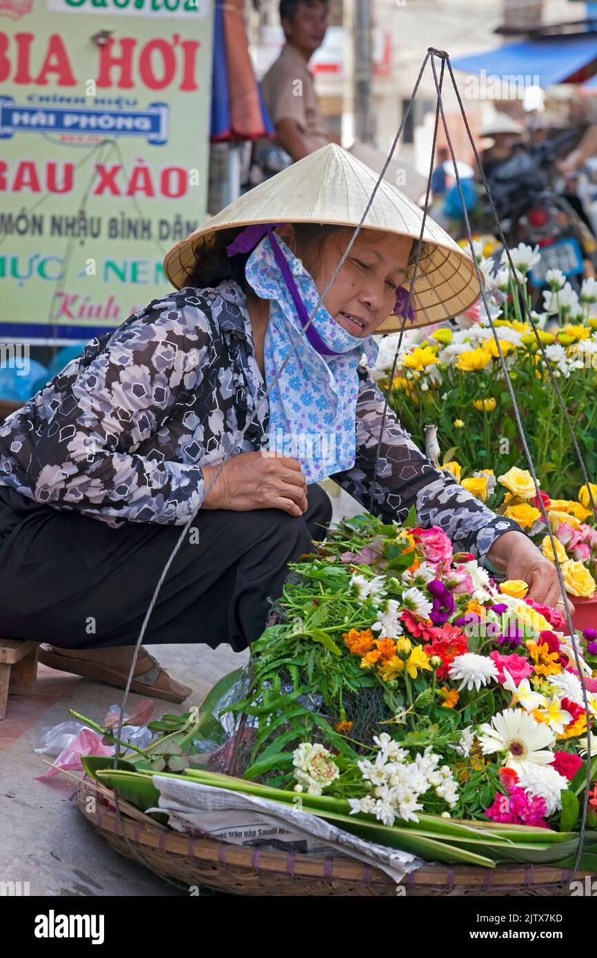 Vietnamese lady florist wearing bamboo hat selling flowers in street ...