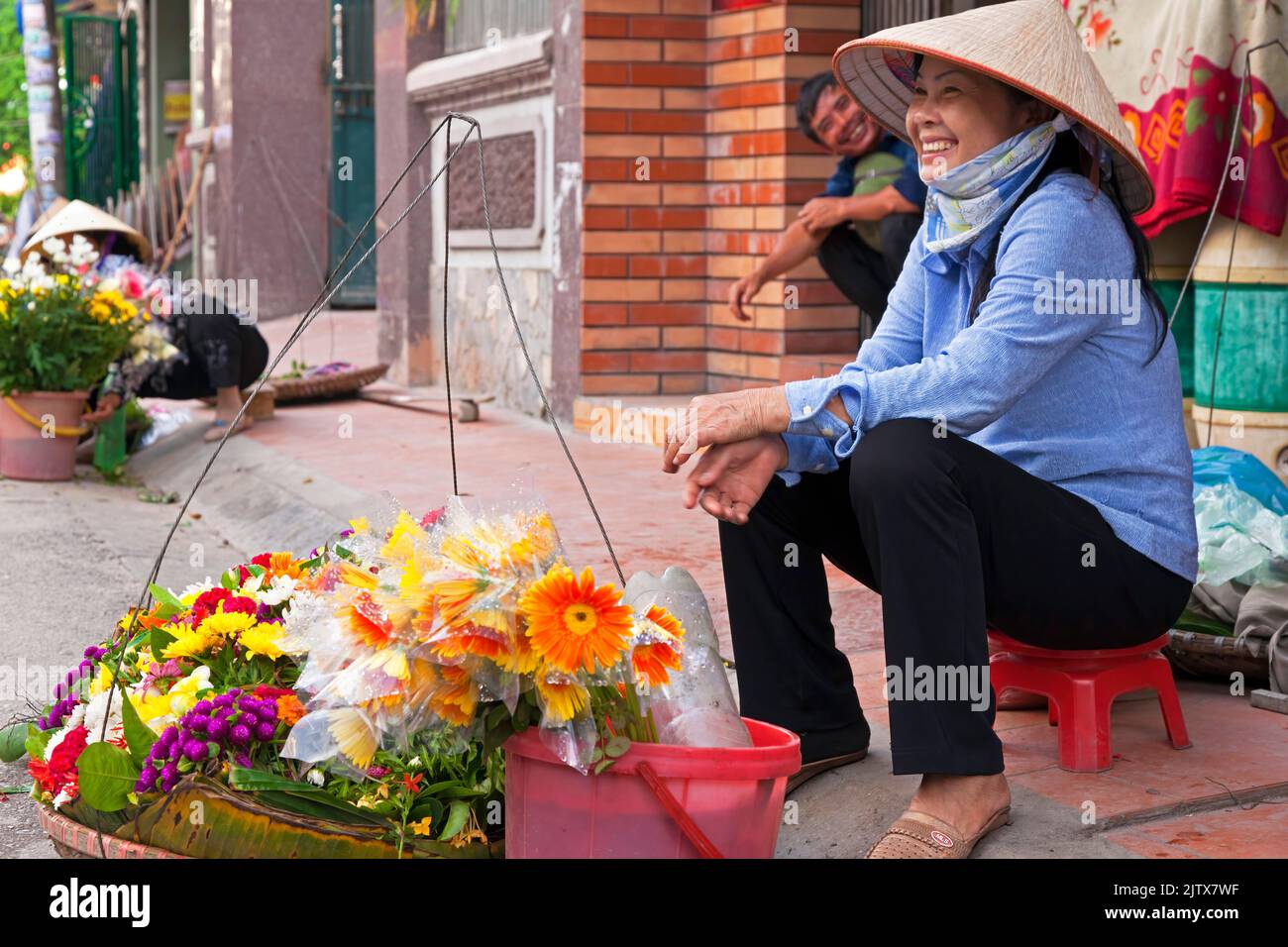 Vietnamese lady florist wearing bamboo hat selling flowers in street ...