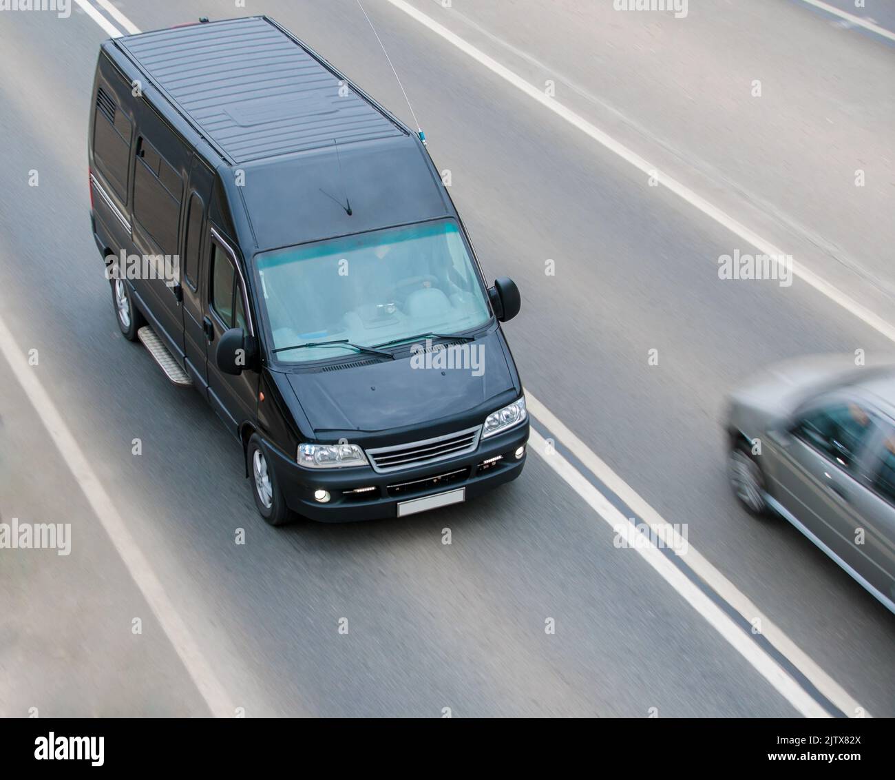 Black cargo minibus driving on the freeway outside the city mid-plan ...