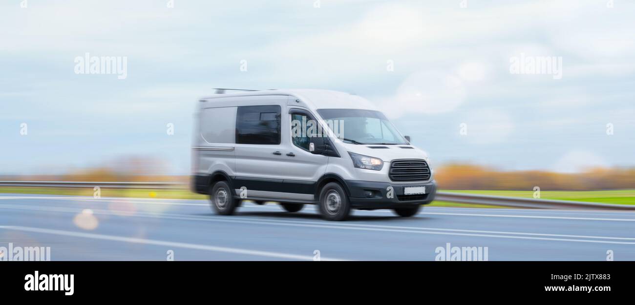 Silver cargo minibus driving on the freeway outside the city mid-plan ...
