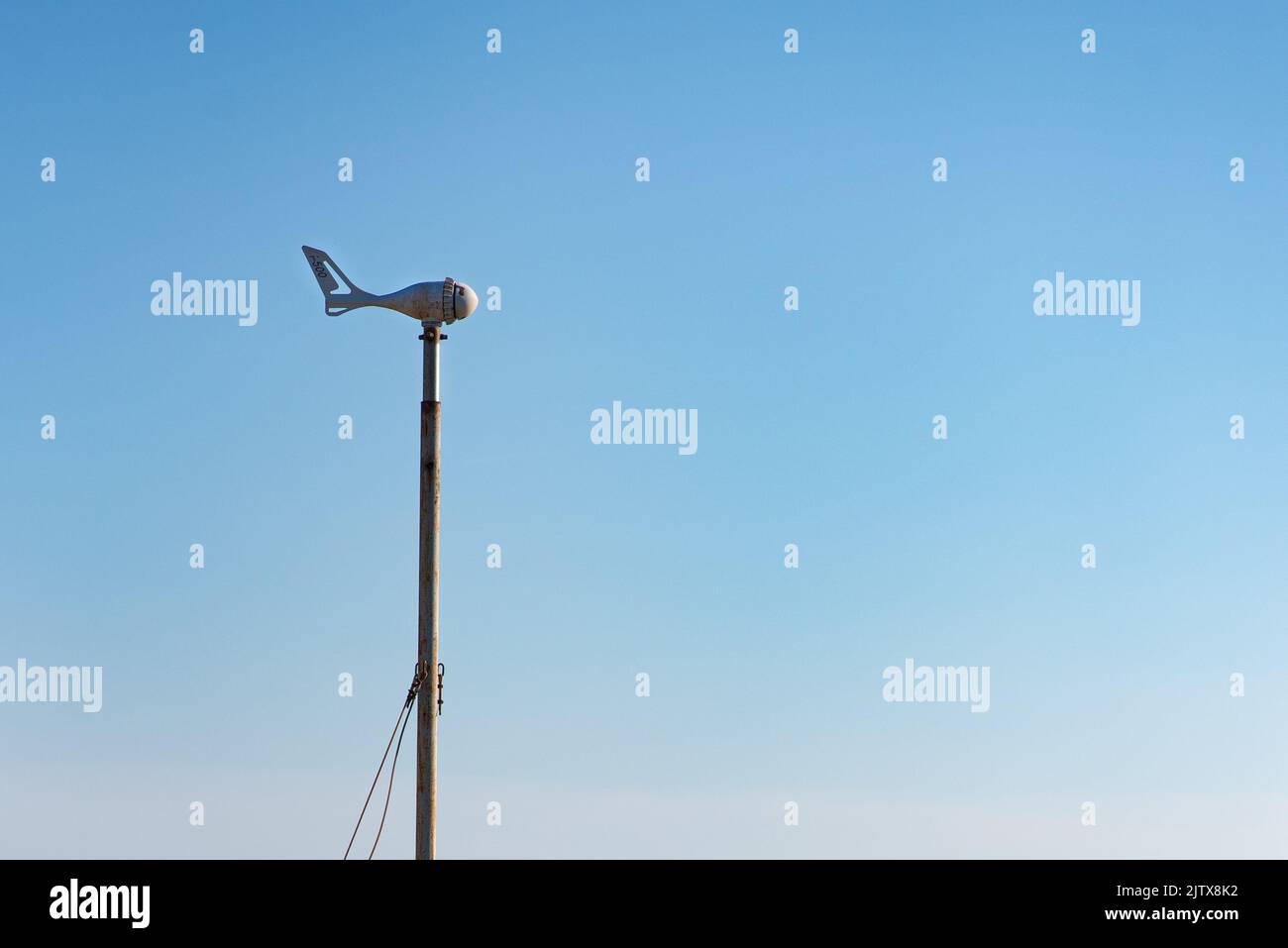 A plane-type anemometer on a post against a blue sky background Stock ...