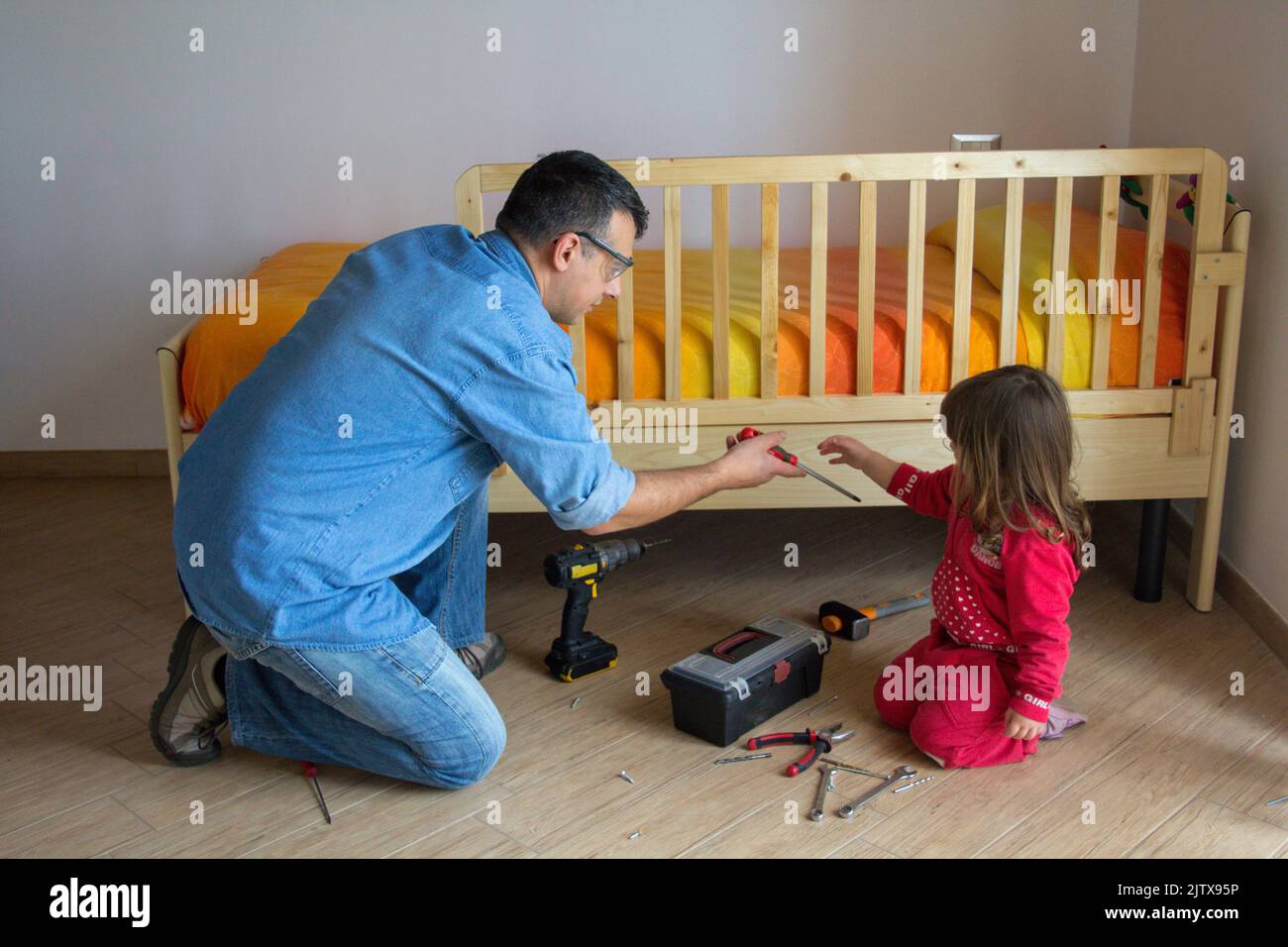 Picture of an adorable little girl helping her handyman dad by handing ...