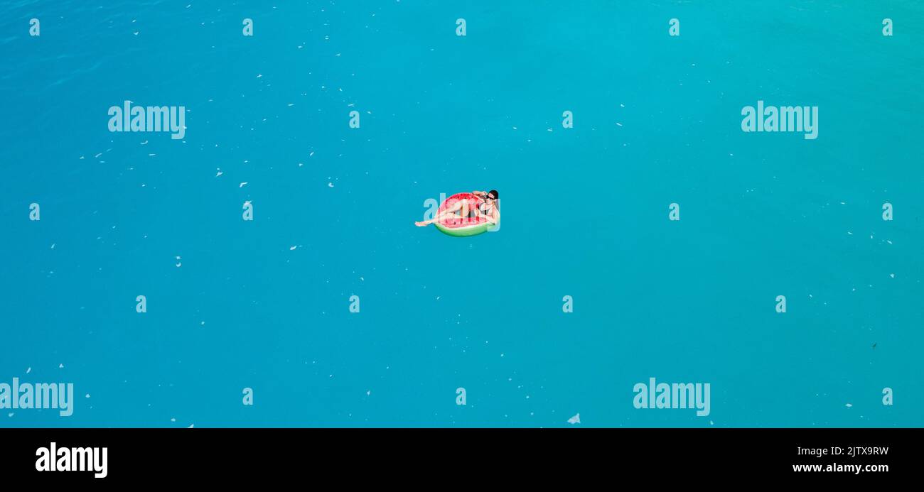 overhead view of woman floating on inflatable ring in blue sea water ...