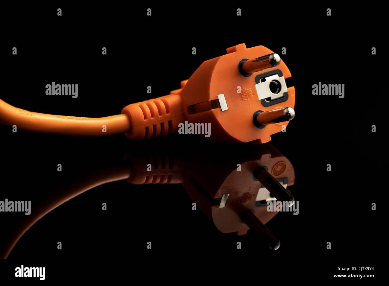 Orange electric plug on the black background Stock Photo - Alamy