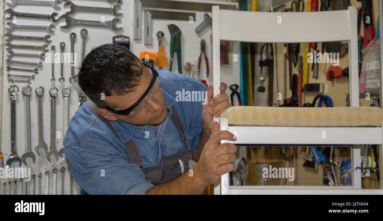 Man carpenter struggling with the restoration of old chairs. Craft work ...
