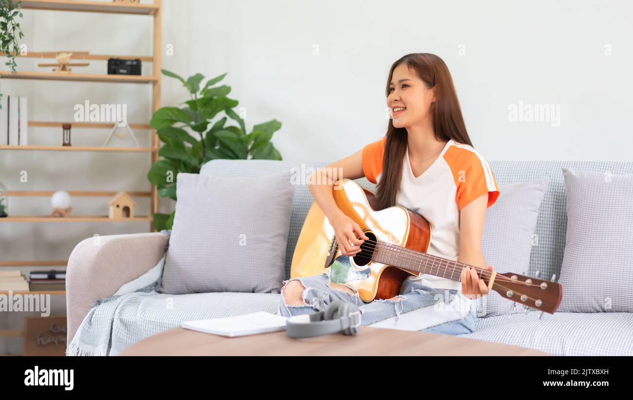 Guitar and singer concept, Young asian woman sitting on couch to ...
