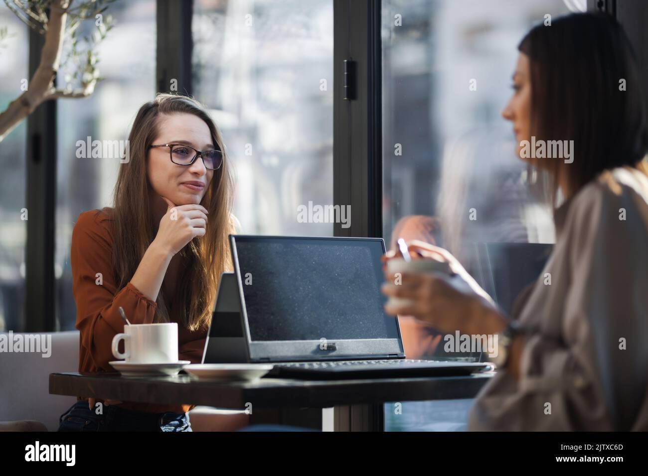 Two young business women in a cafe having one on one meeting. Friends ...