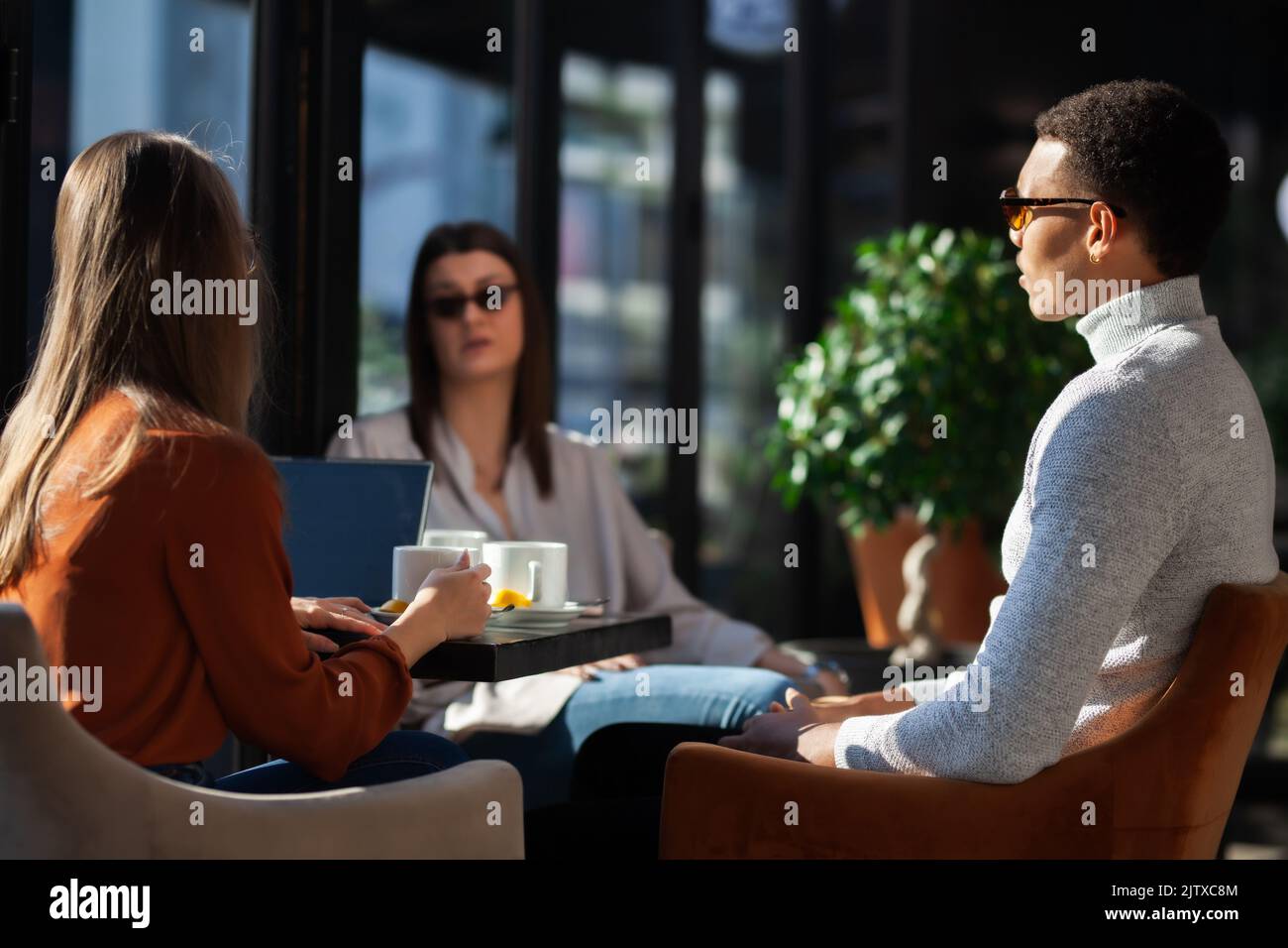 Three friends in a restaurant talking smiling and drinking tea ...