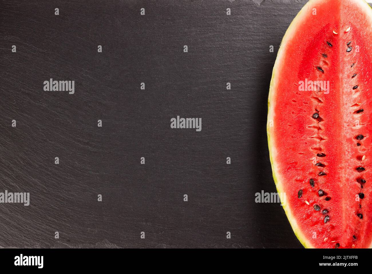 Slice of watermelon on black slate surface.Top view, flat lay, mockup with copy space for text ...