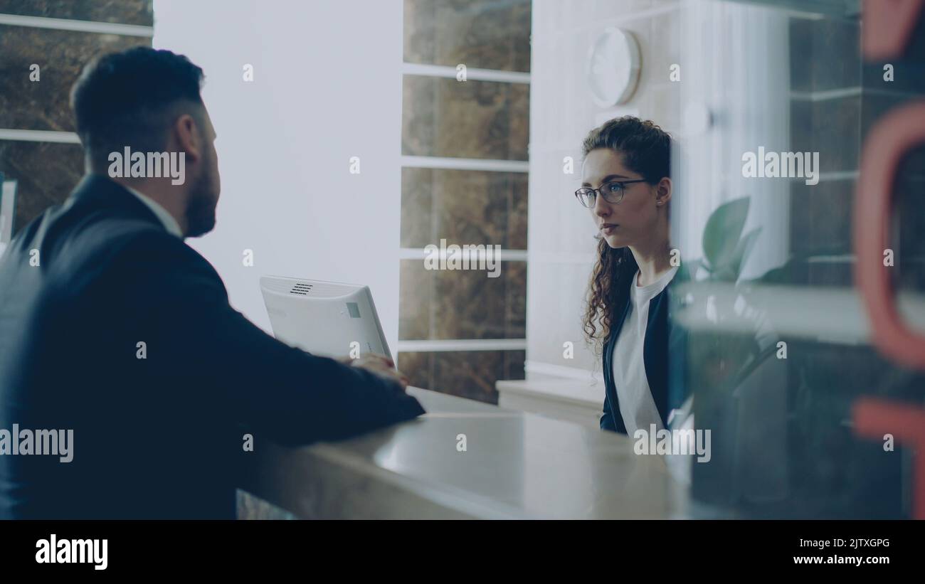 Receptionist girl talking with just arrived businessman about check-in ...