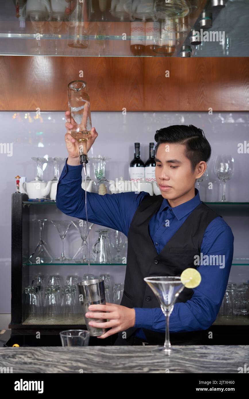 Young Vietnamese bartender pouring vodka into shaker Stock Photo - Alamy