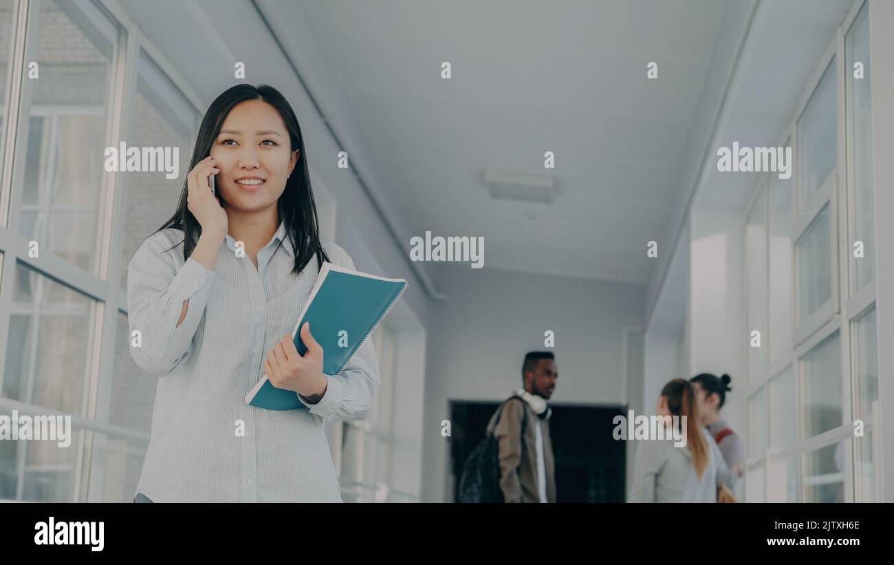 Portrait of young beautiful female student of asian ethnicity talking ...