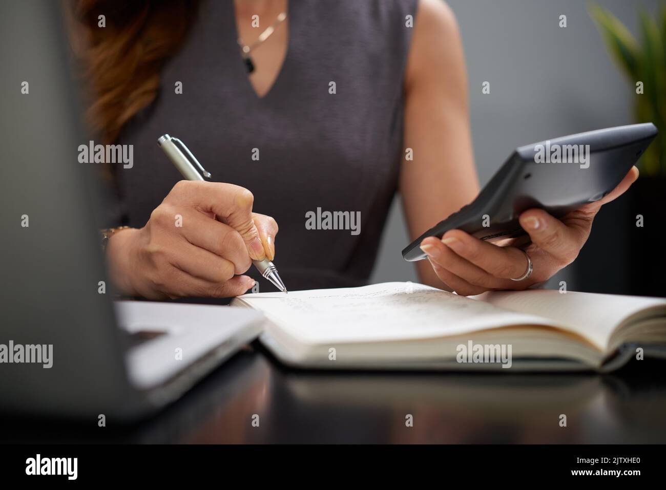 Close-up image of business lady making calculations and taking notes ...