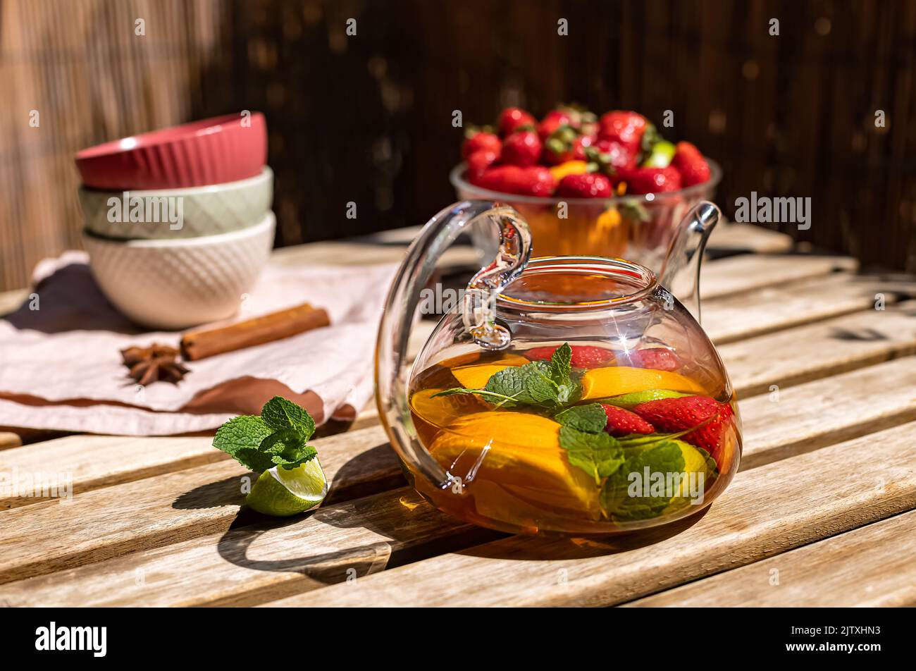 Fruit red tea with berries in a glass teapot on the sunny balcony Stock ...
