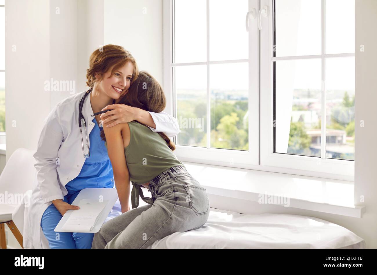 Friendly doctor supporting and hugging child during health checkup in ...