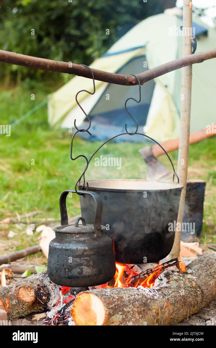 Two smoked tourist kettles over camp fire. Process of cooking on the ...
