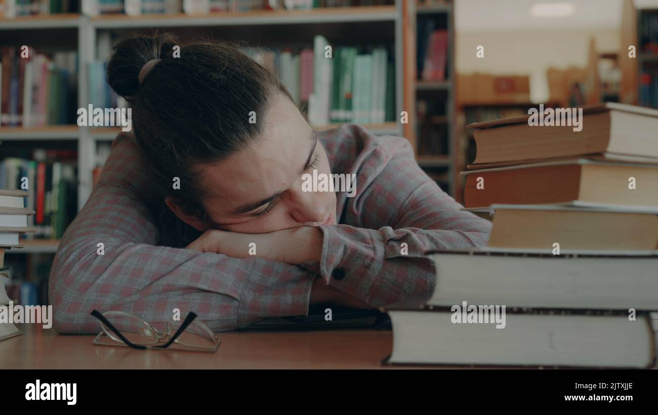Handsome young caucasian man sitting with his head on table is sleeping ...