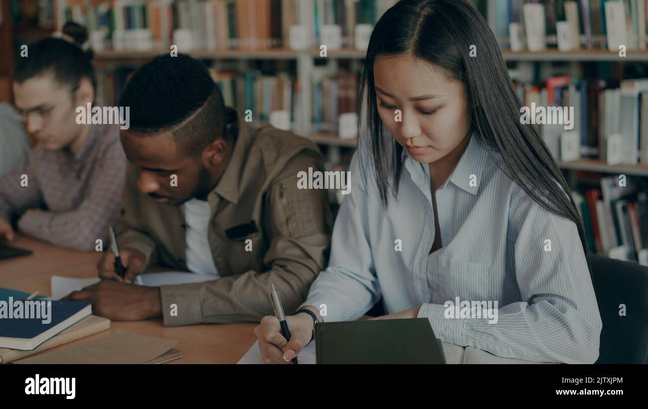 Concentrated asian girl student preparing for examination and writing ...