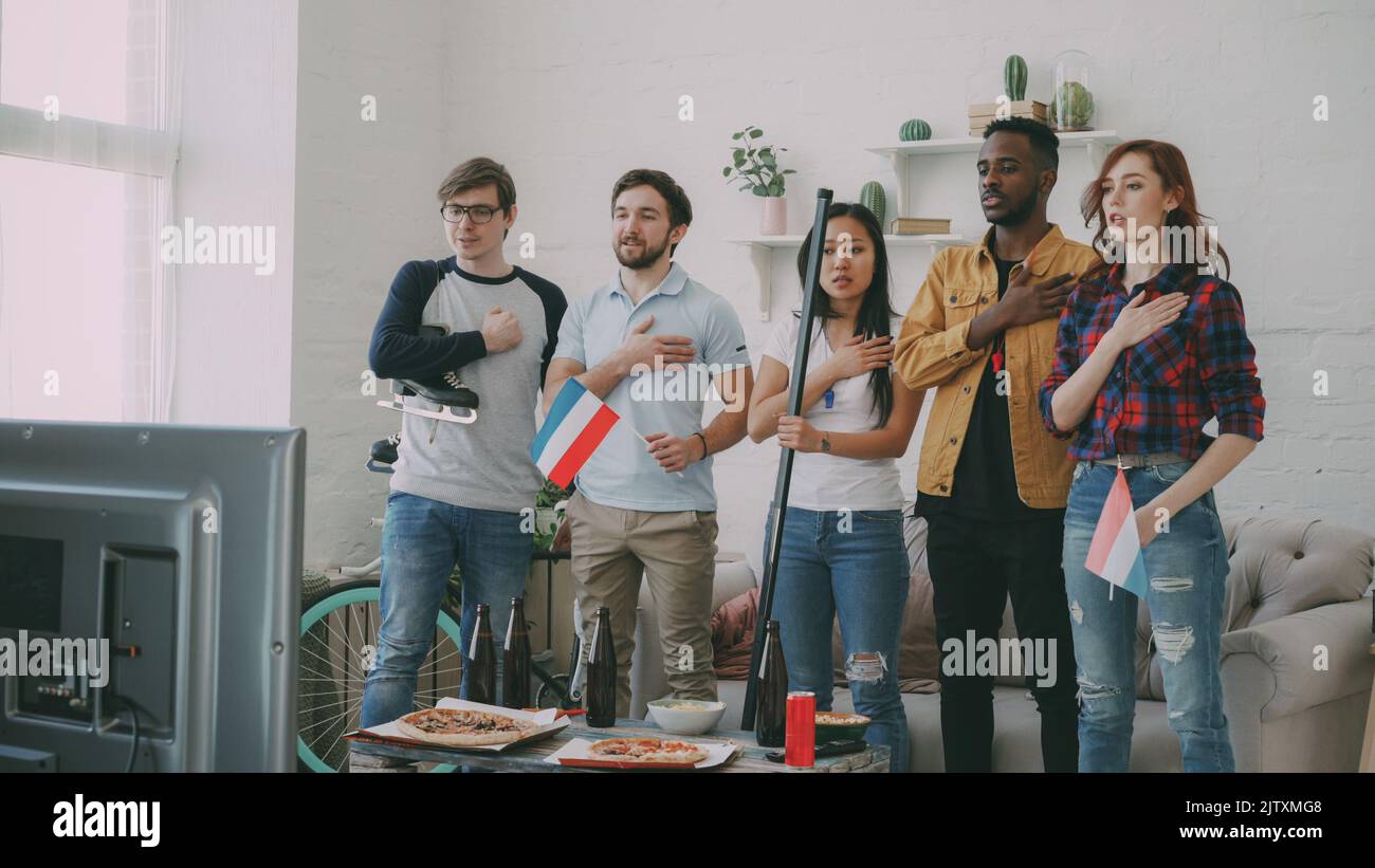Multi ethnic group of friends sport fans listening and singing Dutch ...