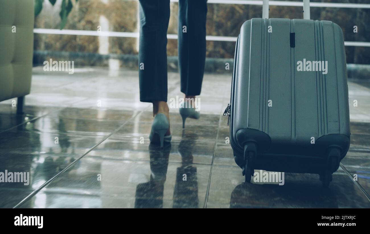 legs of businesswoman walking through hotel lobby pulling luggage and ...