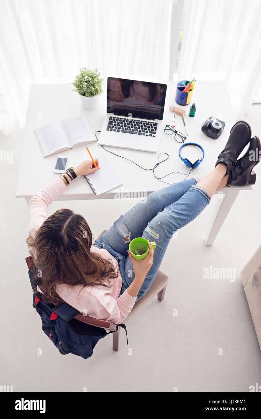 Female colledge student sitting with feet on her table and doing ...