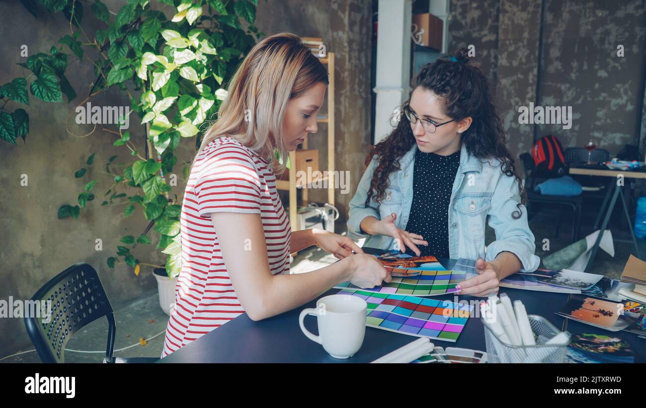 Attractive female designers are busy working with color palettes to ...