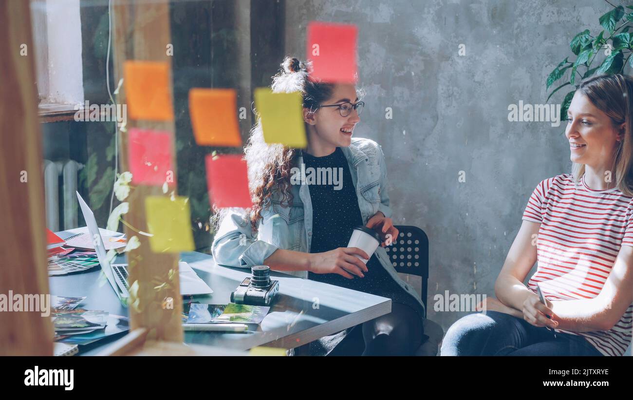 An attractive young designer is talking to her colleague in workplace ...