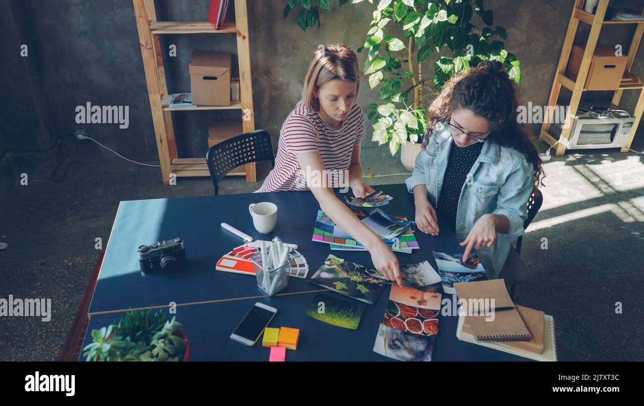 High angle view of young female designers are placing photos on broad ...