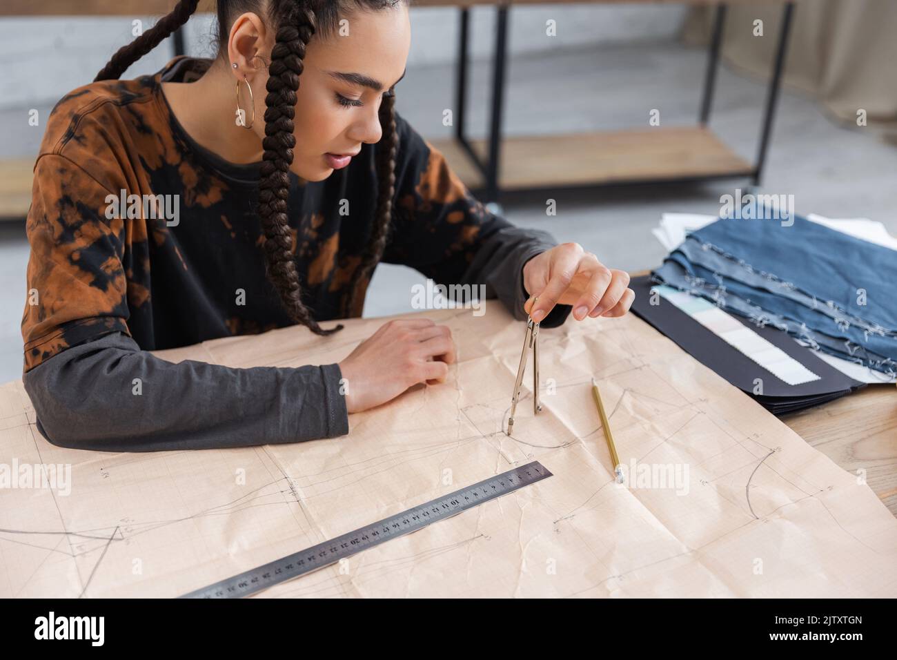 African american designer drawing with compass on sewing pattern in ...