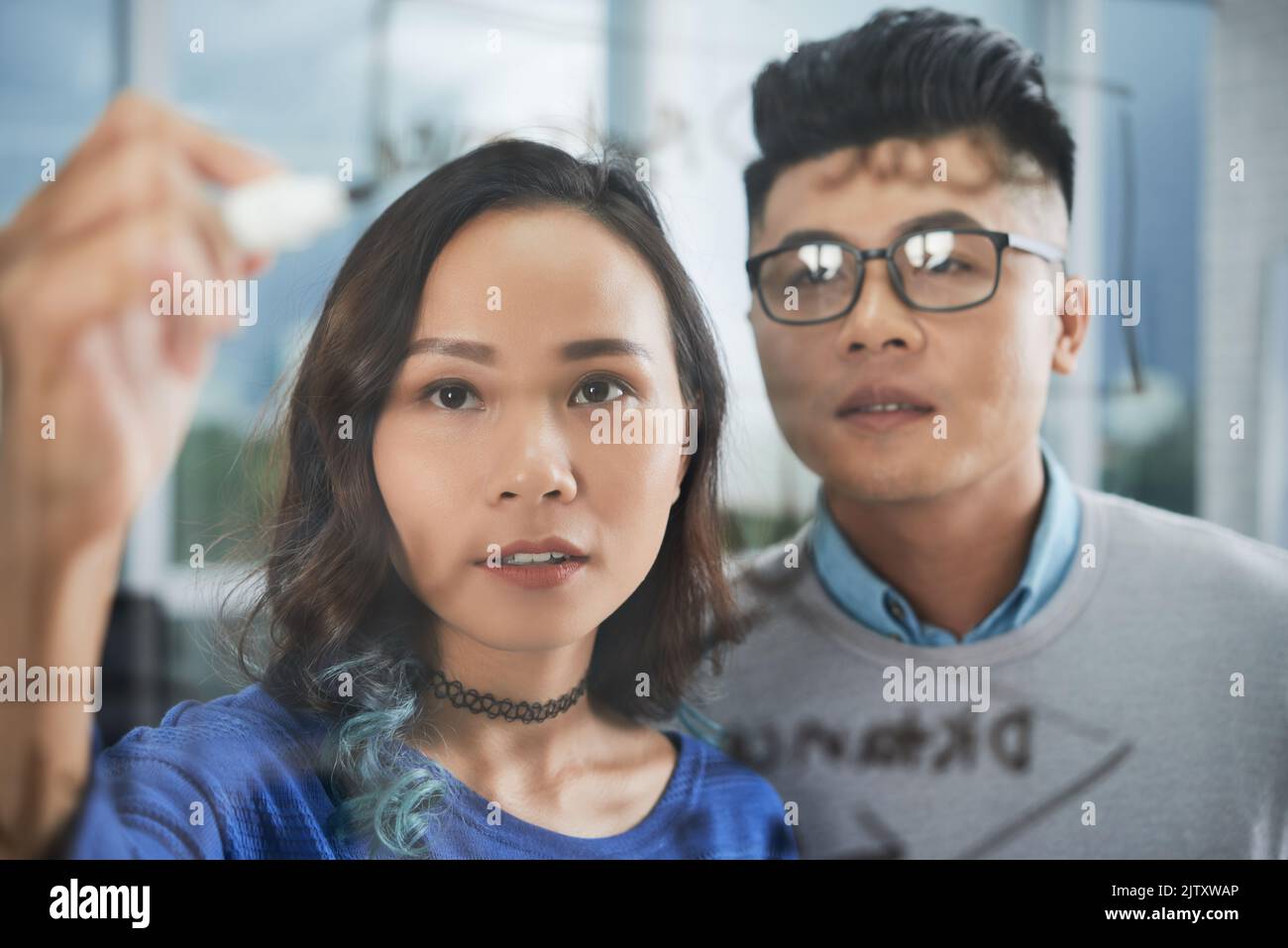 Asian young couple writing on glass wall at office Stock Photo - Alamy