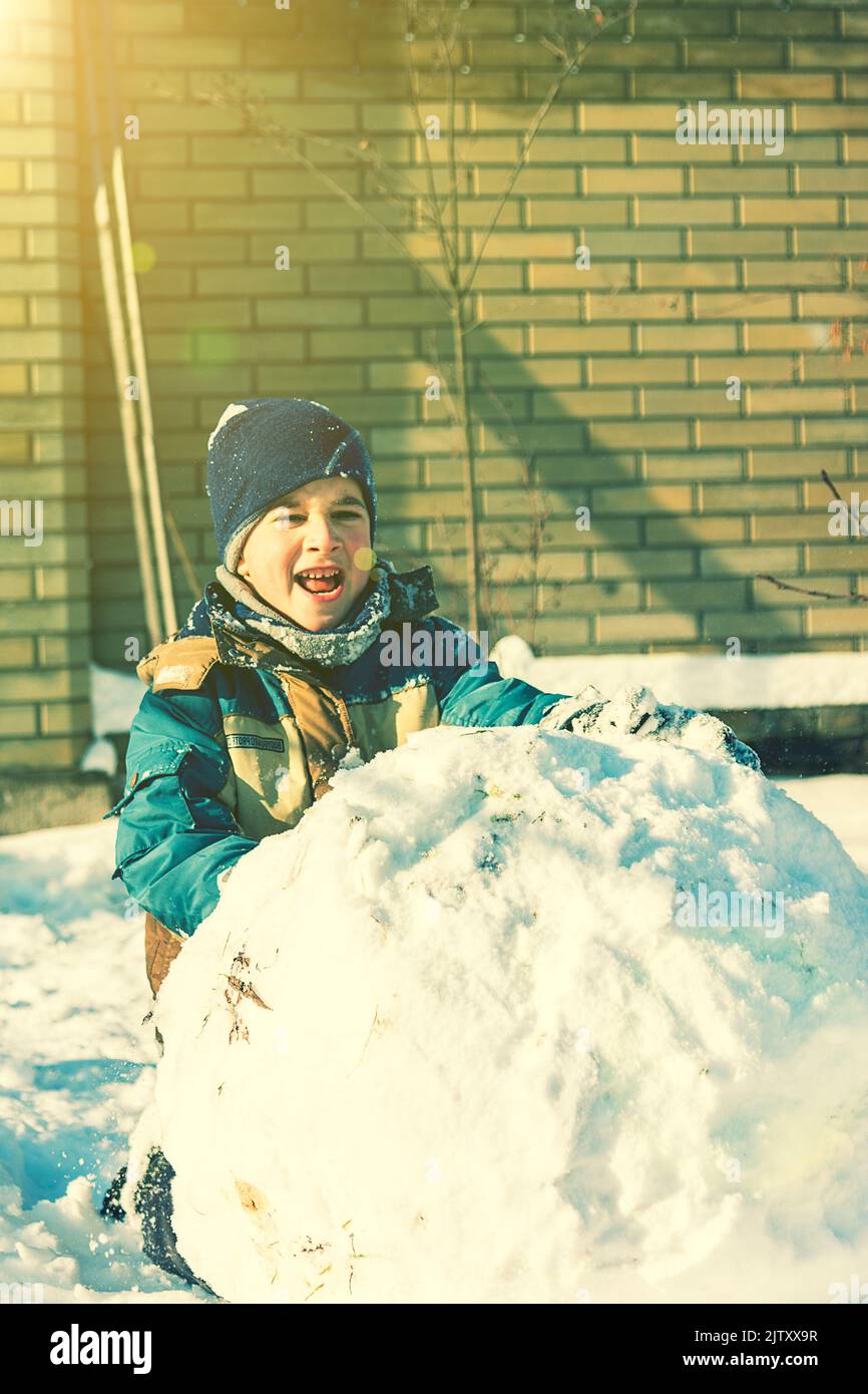 boy sculpt a snowman in the backyard of the house clear winter day. The ...