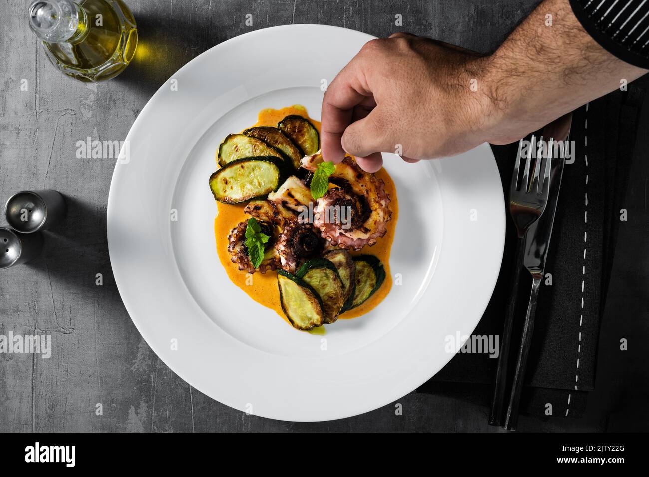 cooked octopus, served with courgettes and sauce serving on the table ...