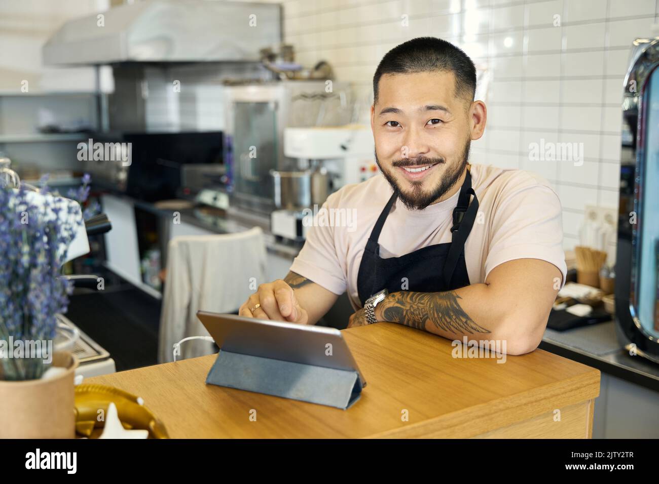 Friendly bearded barista looking inviting at coffee shop counter Stock ...