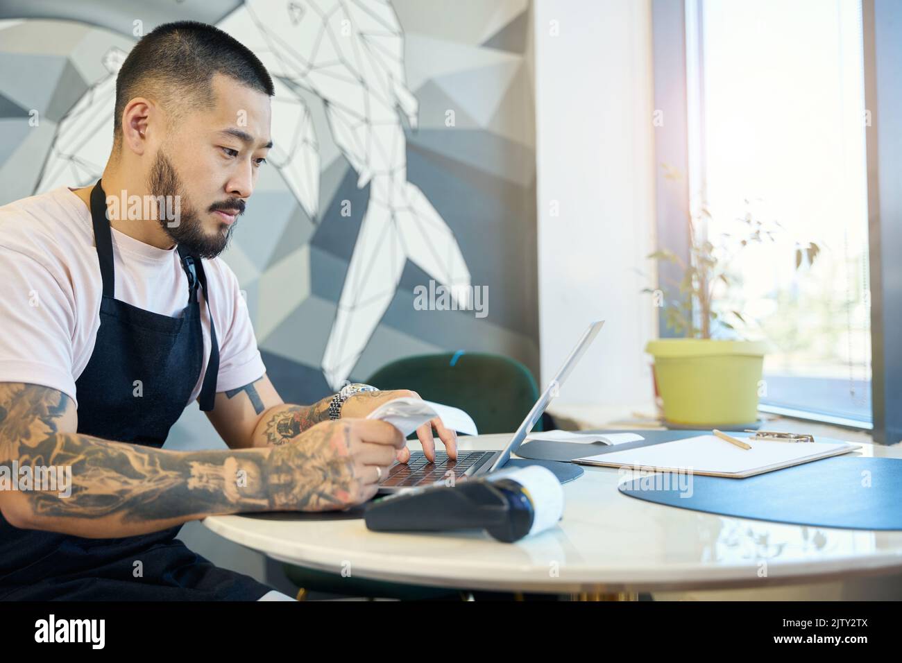 Young man working as cafe accountant and processing payments Stock ...