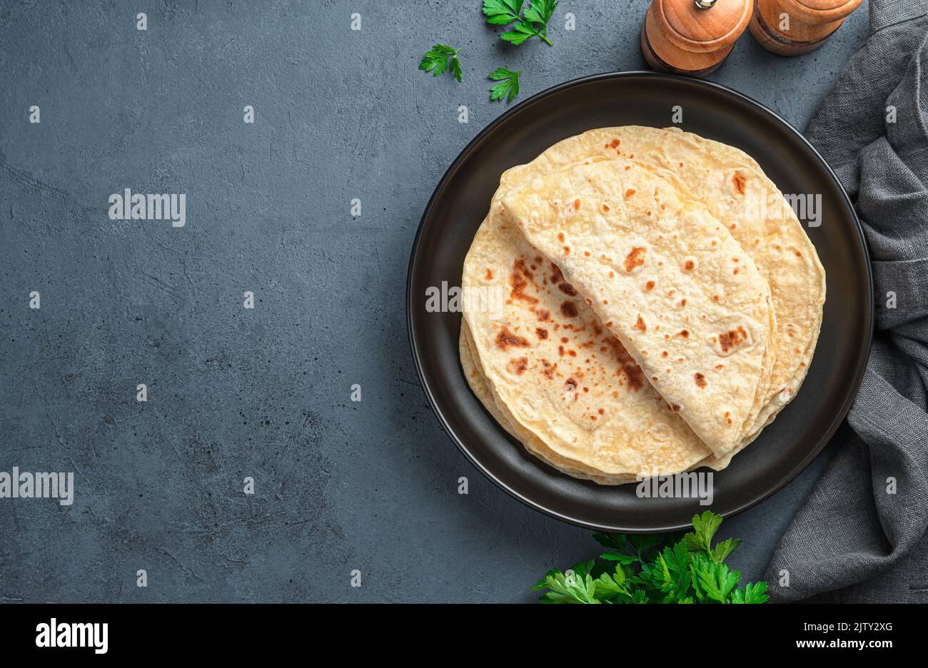 Fresh Indian chapati tortillas with fresh parsley on a graphite ...