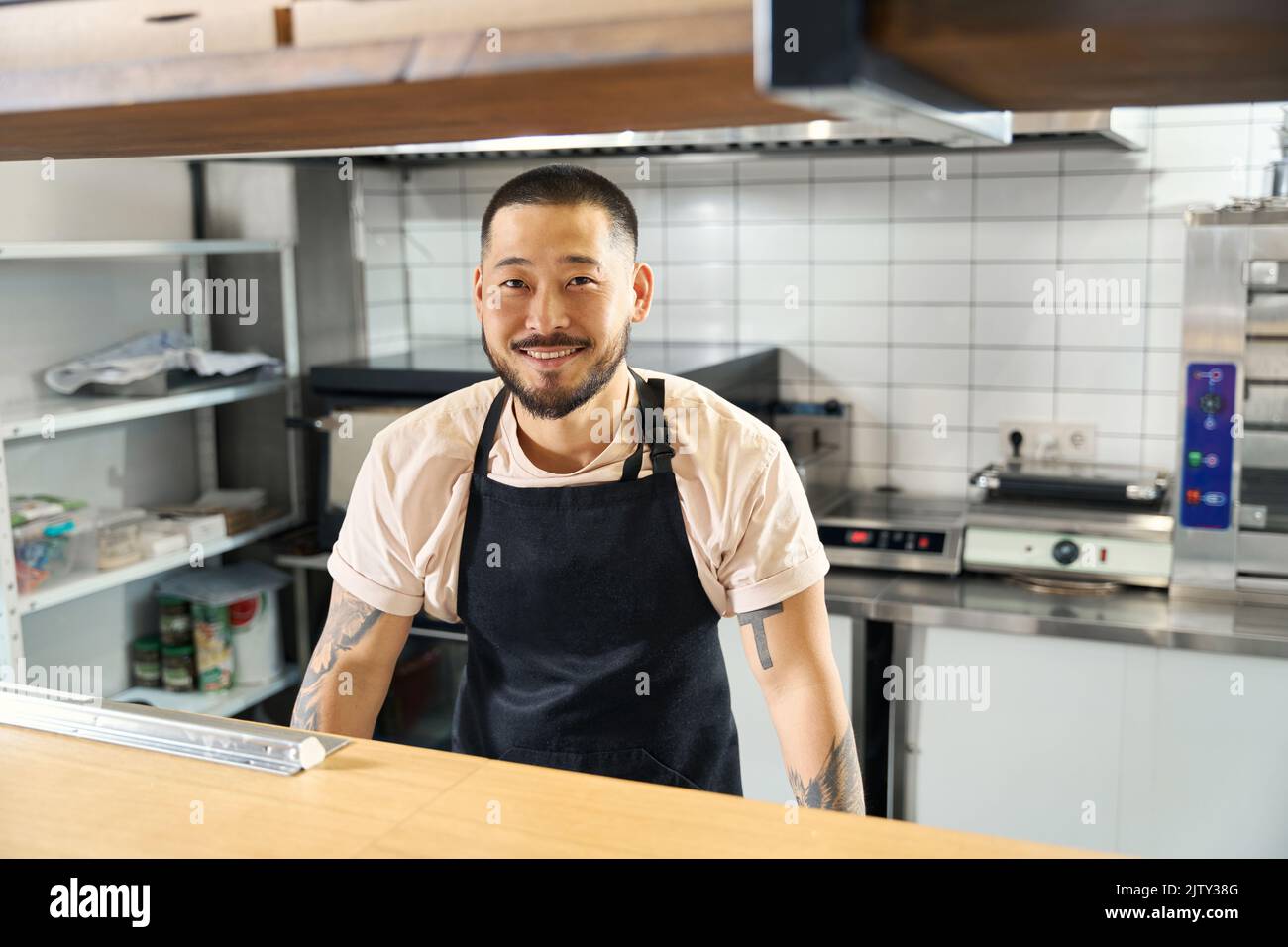 Cheerful young chef posing happily at his cafe workplace Stock Photo ...