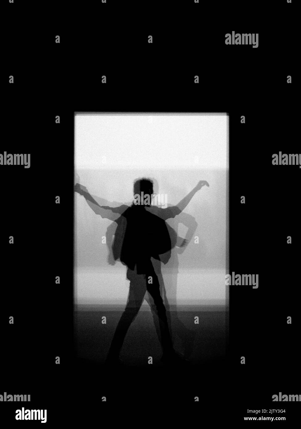 A vertical shot of a moving silhouette of a man in front of a white ...