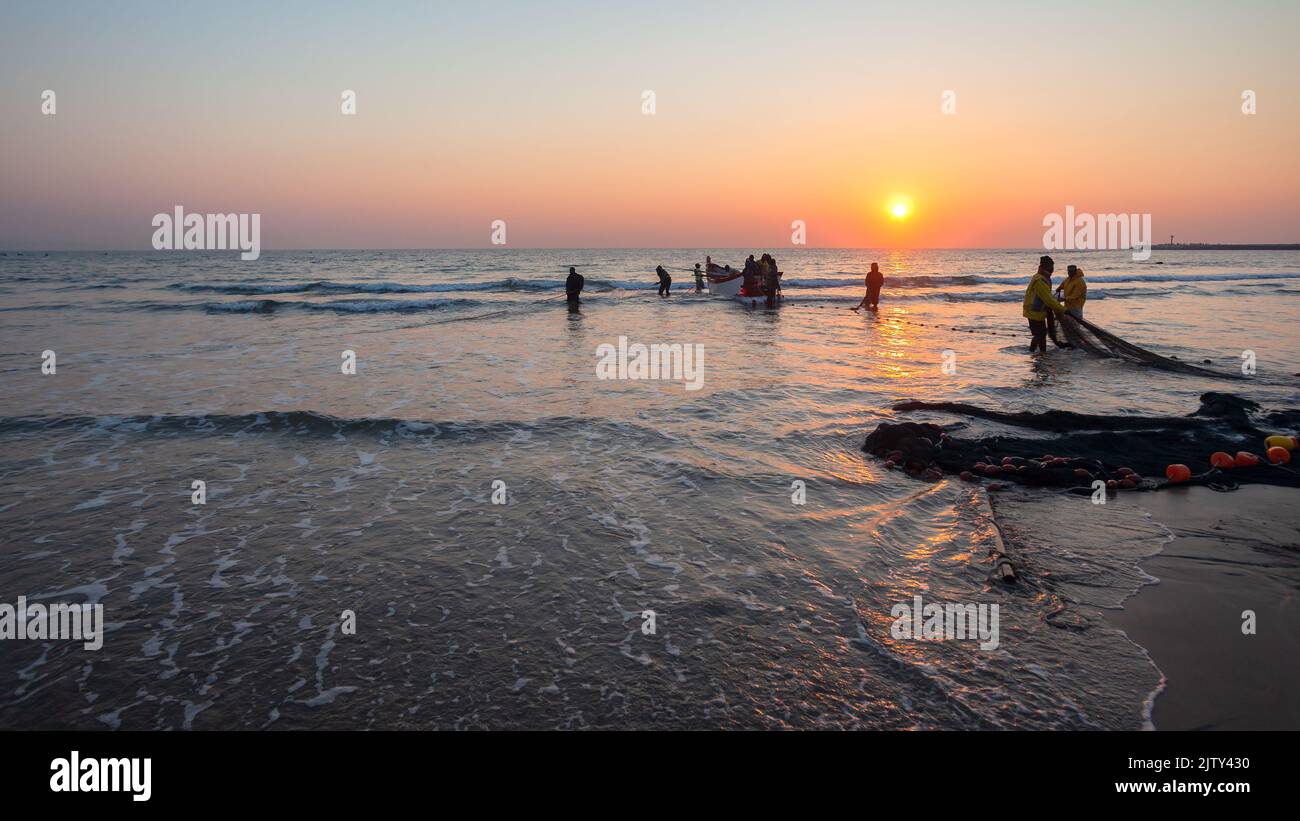 Fishermen preparations for rowing boat fishing nets on beach shoreline ...