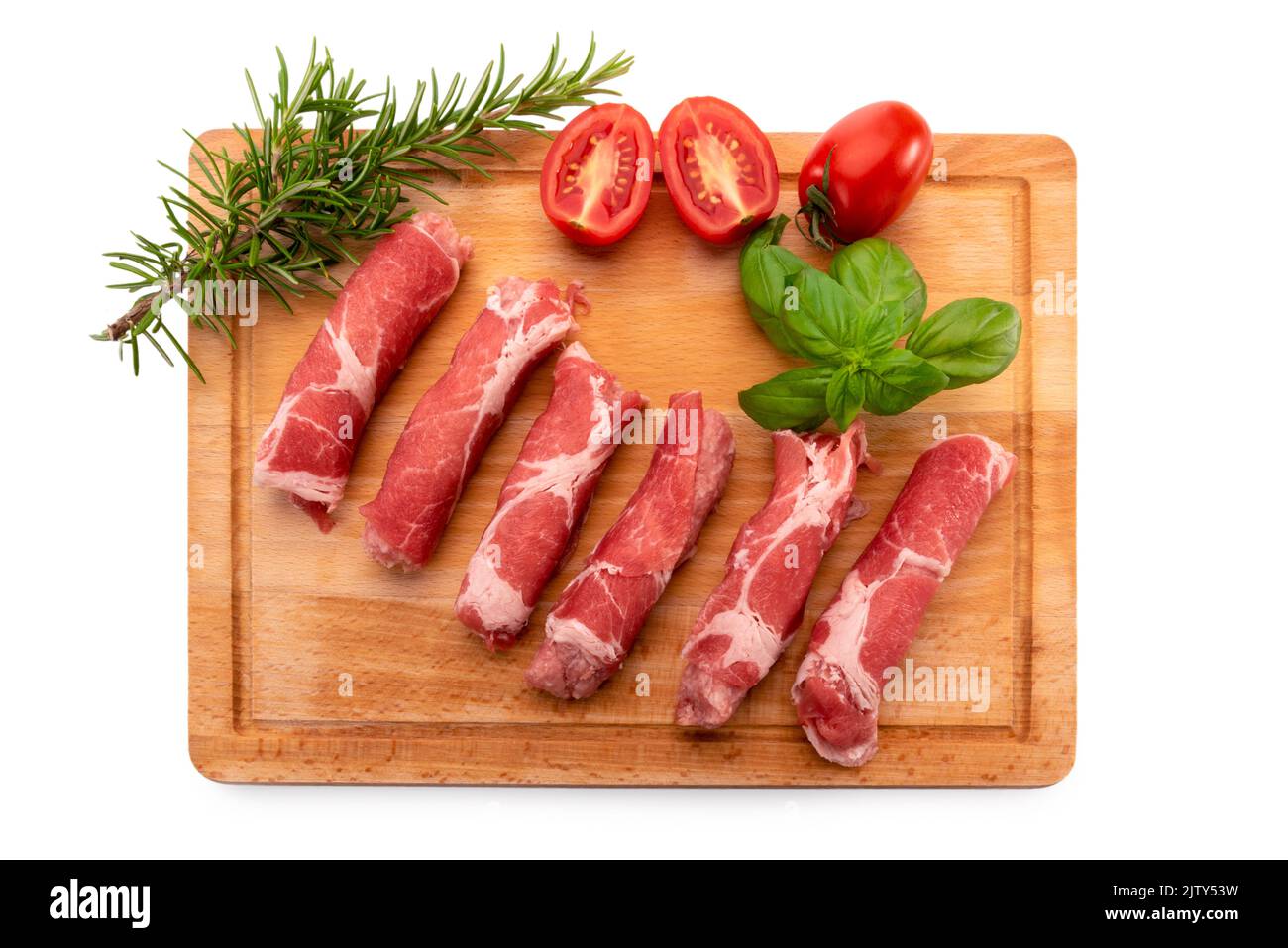 Raw pork neck steak rolls (coppa) on wooden cutting board with rosemary ...