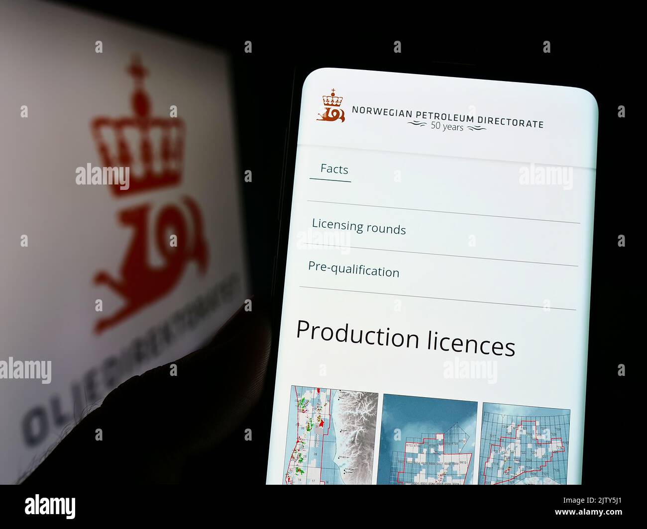 Person holding cellphone with webpage of agency Norwegian Petroleum ...