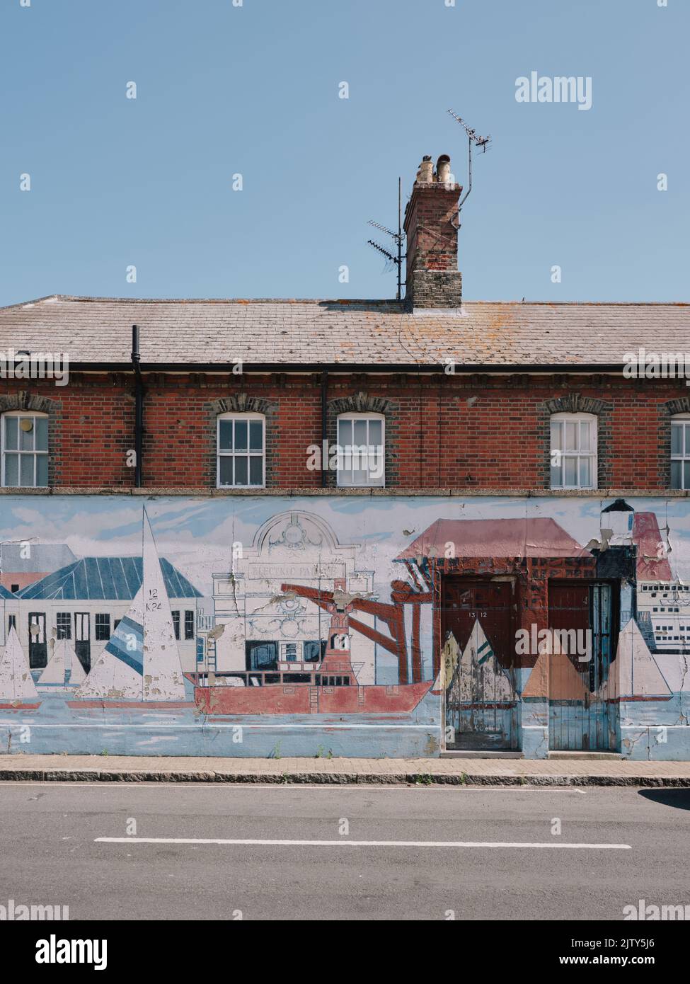 The architecture and empty street with mural art along a boarded up brick cottage terrace of ...