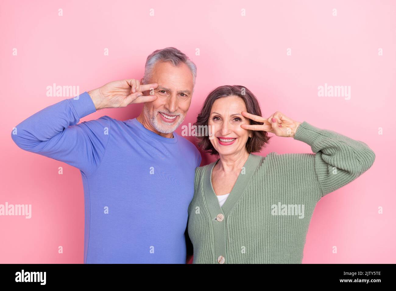 Portrait of two attractive funky cheerful people embracing showing v ...