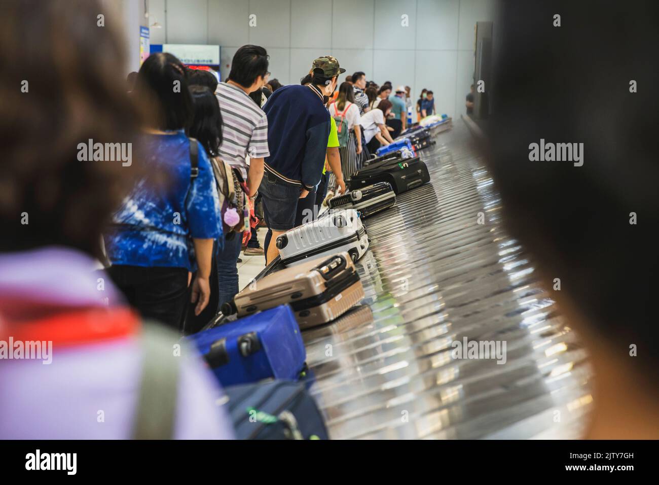 Many passengers waiting suitcase or luggage with circulating conveyor ...