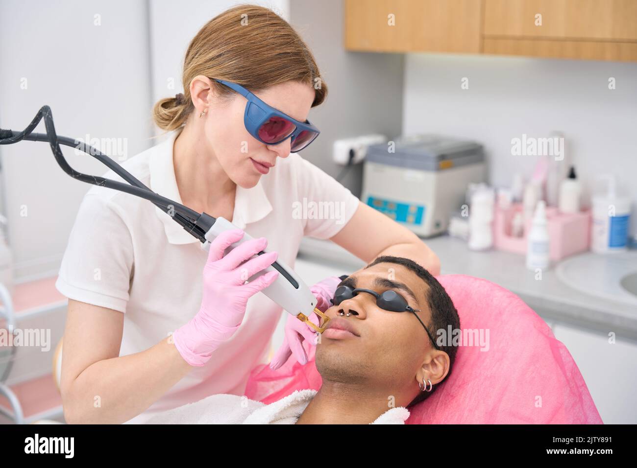 Esthetician performing laser epilation on man face with modern ...